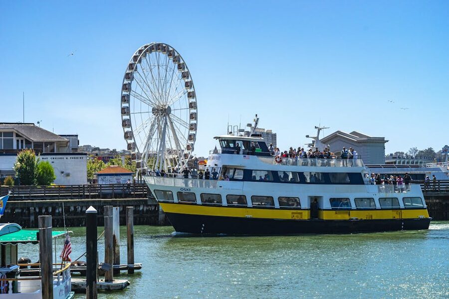 Ferry full of passengers sailing past Pier 39 Ferris wheel