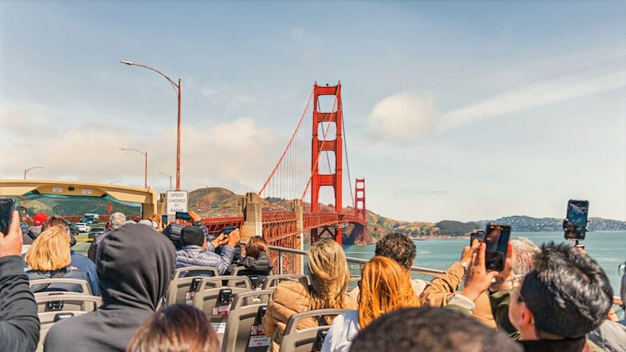 Tourists on an open-top bus photographing the Golden Gate Bridge
