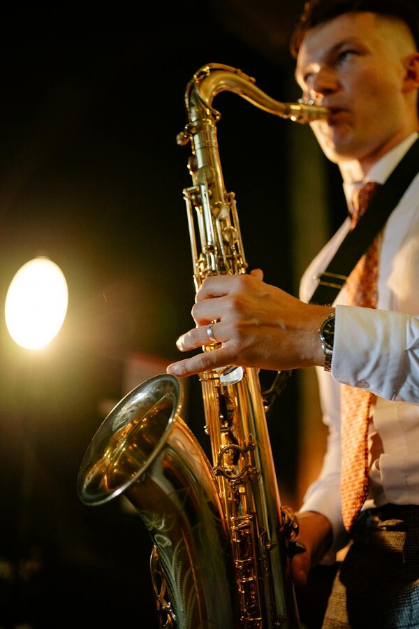 Saxophonist playing on stage during a live concert under warm lights
