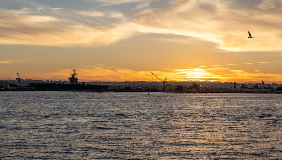 San Diego Bay at sunset with an aircraft carrier silhouetted on the horizon