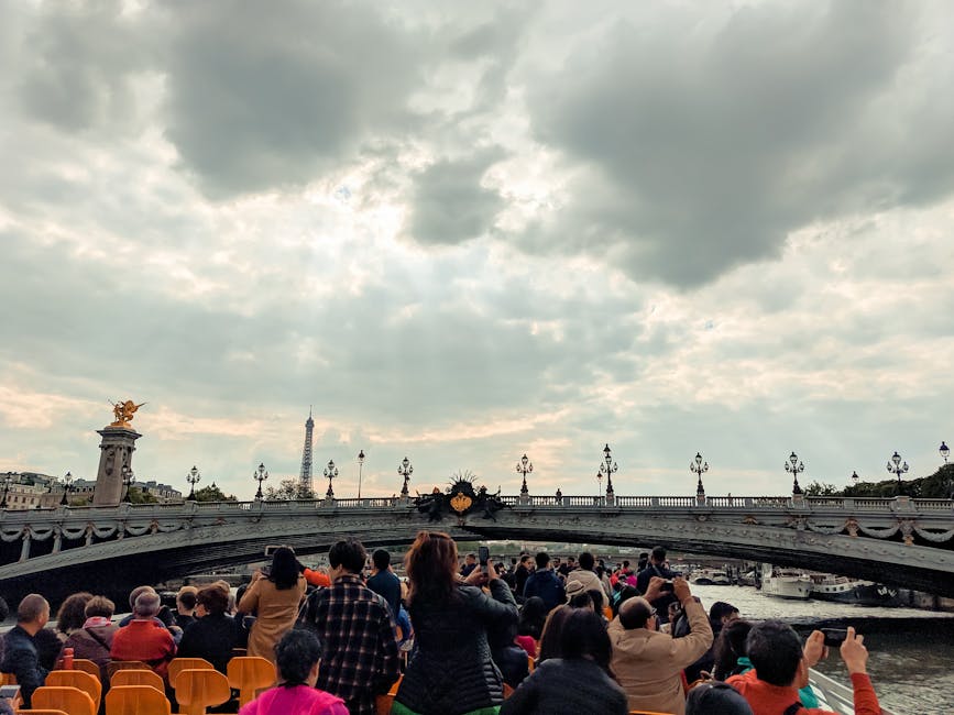 Cruise tourists on top deck photographing Pont Alexandre III with Eiffel Tower in view
