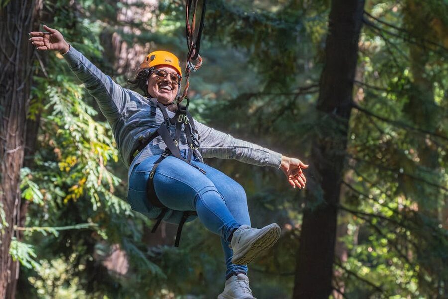 Woman smiling on a zipline through a lush forest