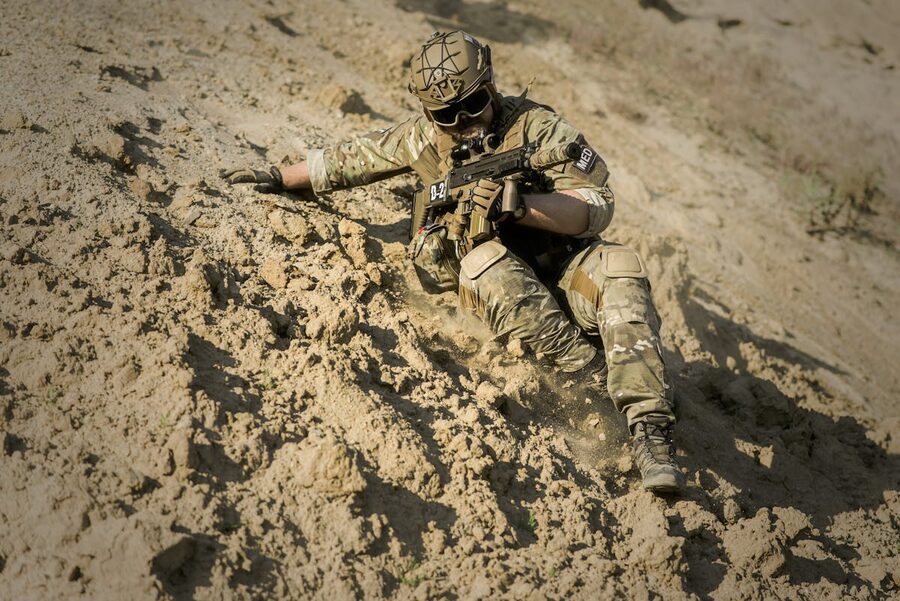 Soldier in camouflage gear on sandy slope desert