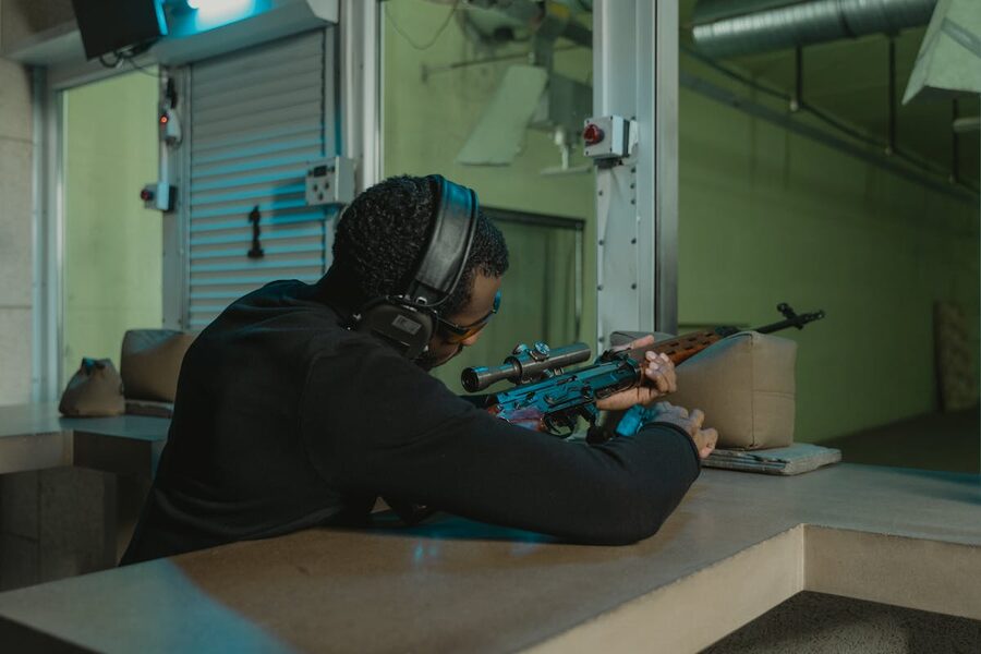 Man aiming rifle at indoor shooting range with concentration
