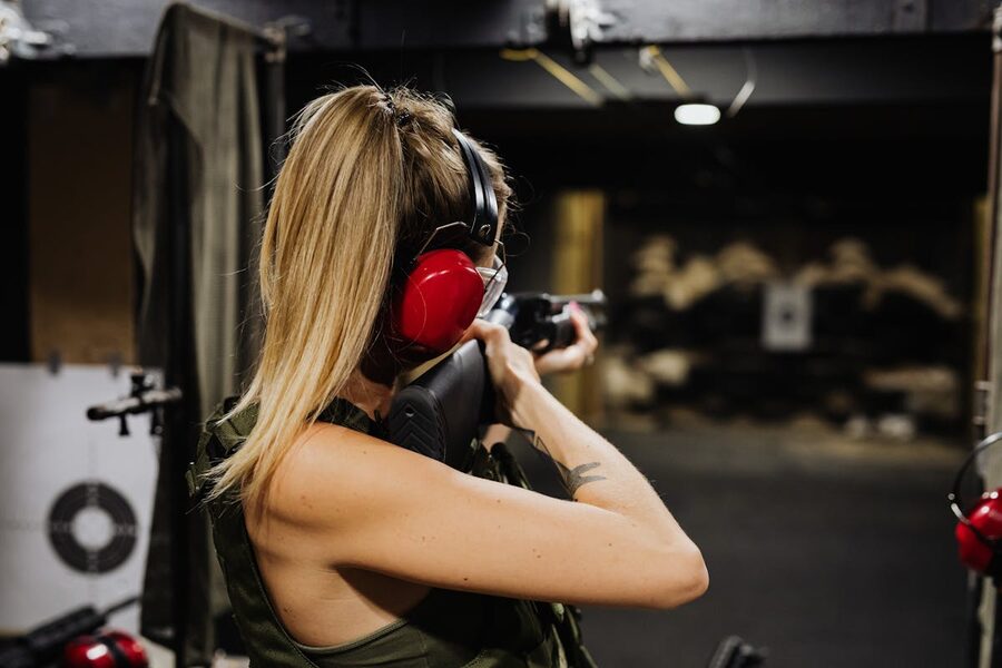 Woman aiming rifle at target in indoor shooting range