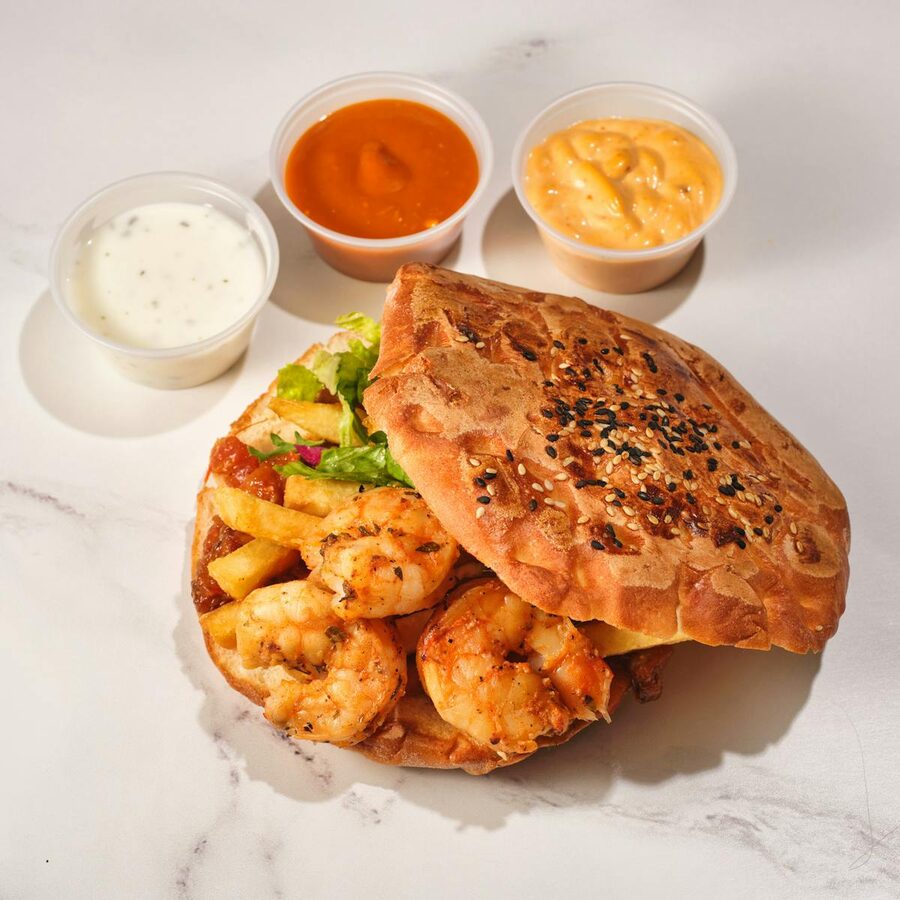 Shrimp po boy sandwich served with crispy fries and assorted sauces