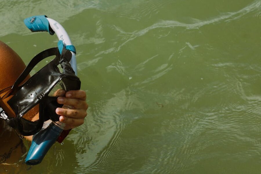 Snorkel mask held above clear spring water