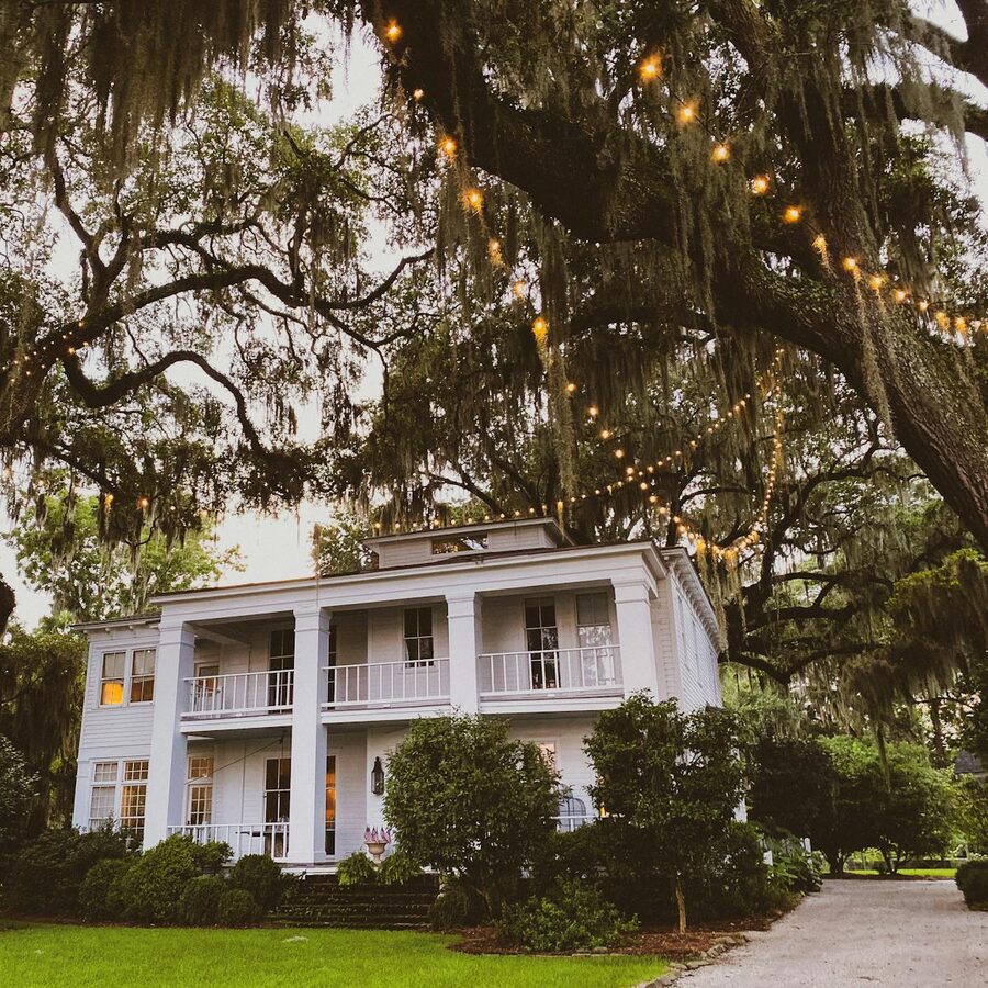 Classic Southern mansion surrounded by greenery and charming string lights