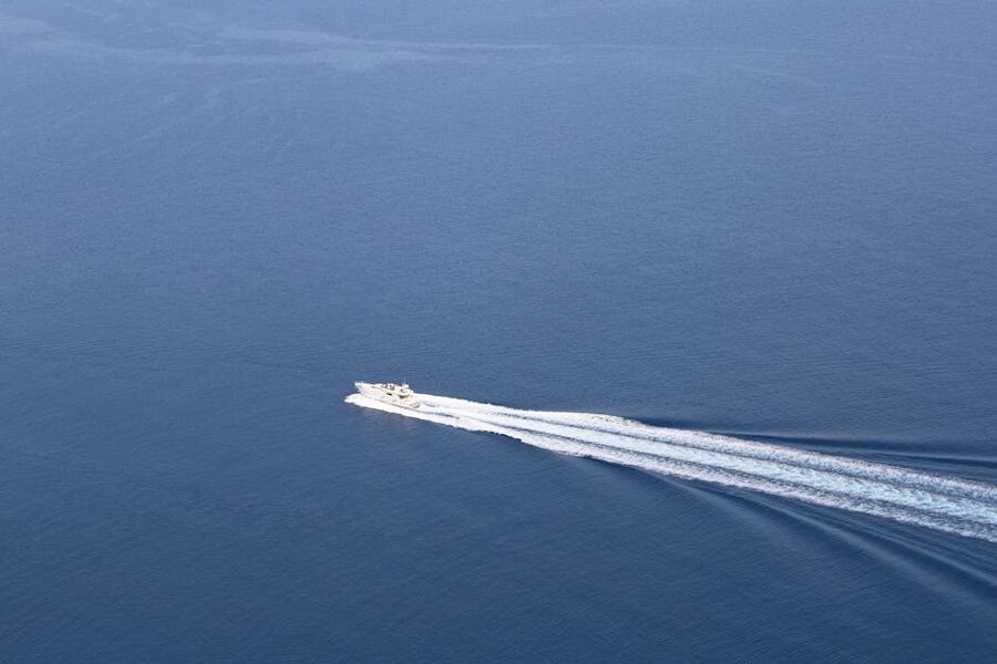 Aerial view of a speedboat cutting through blue ocean with white wake