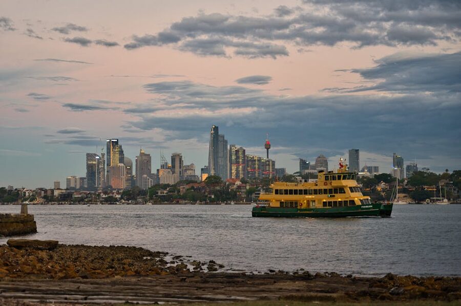 Sydney ferry sailing past harbour skyline at sunset