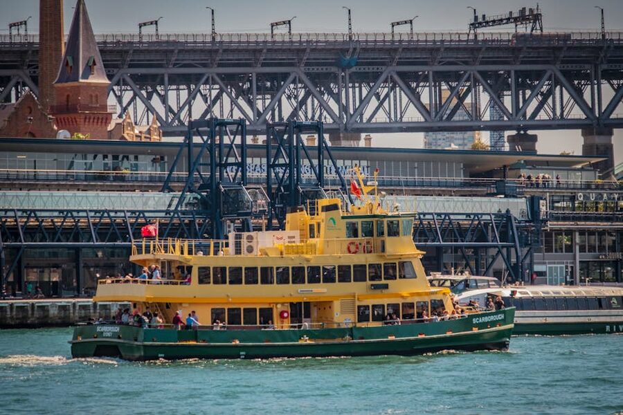 Yellow Sydney ferry passing under Harbour Bridge