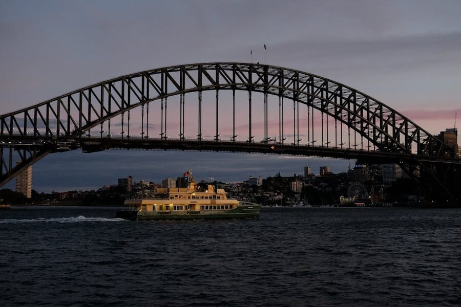 Ferry under Sydney Harbour Bridge at sunset