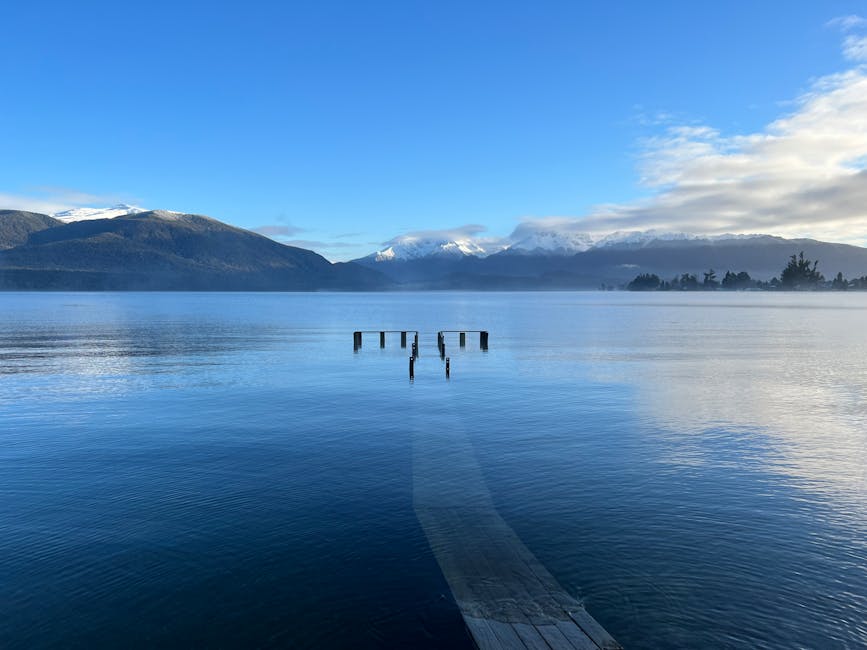 Te Anau jetty at sunrise with calm lake and snow capped mountains