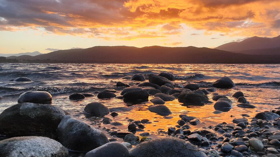 Te Anau lakefront stones at sunset with calm water