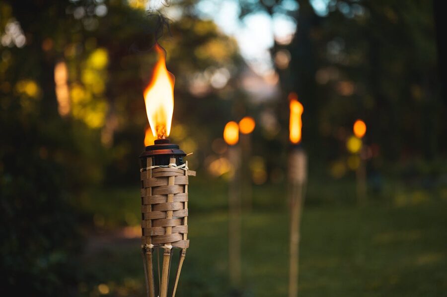 Multiple tiki torches illuminating a garden path with warm inviting glow