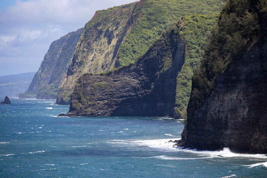 Towering coastal cliffs with crashing ocean waves under clear sky