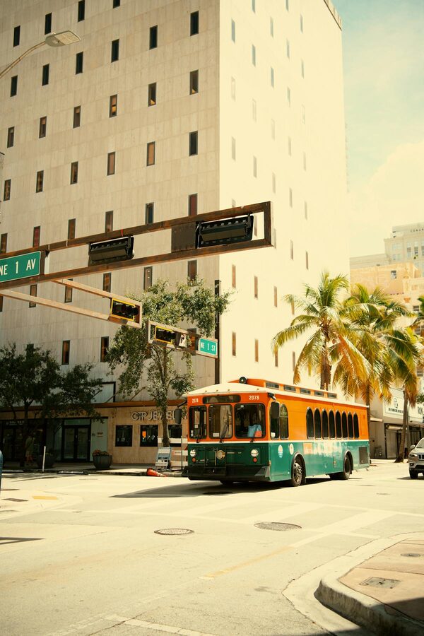 Colorful trolley navigating sunny downtown streets with palm trees