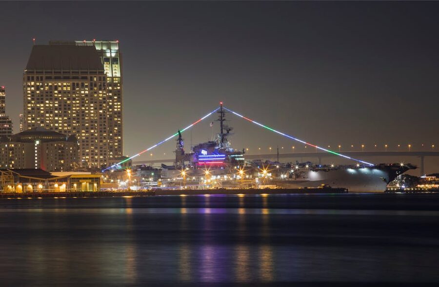 USS Midway Museum at night with the San Diego skyline behind it