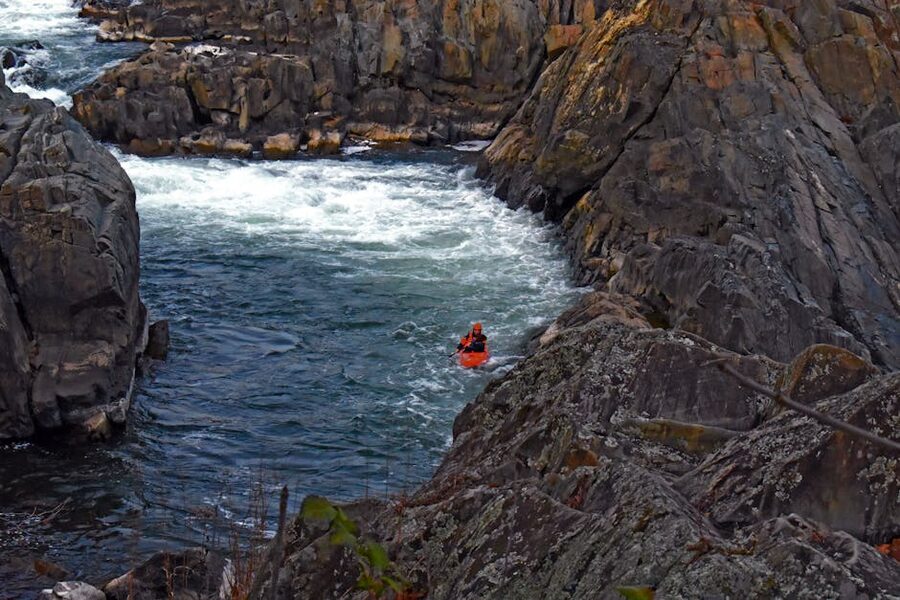 Group of kayakers on calm blue water surrounded by canyon walls