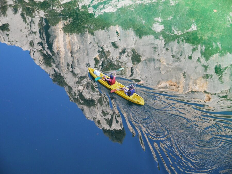 Paddler on clear water with rocky canyon in the background