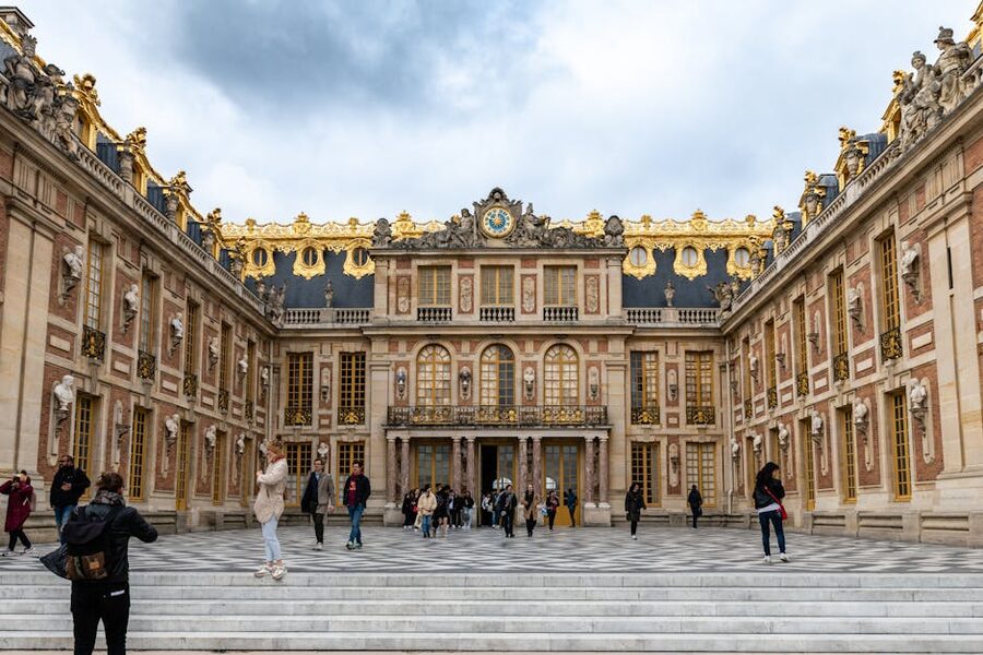 Tourists walking in front of the Palace of Versailles