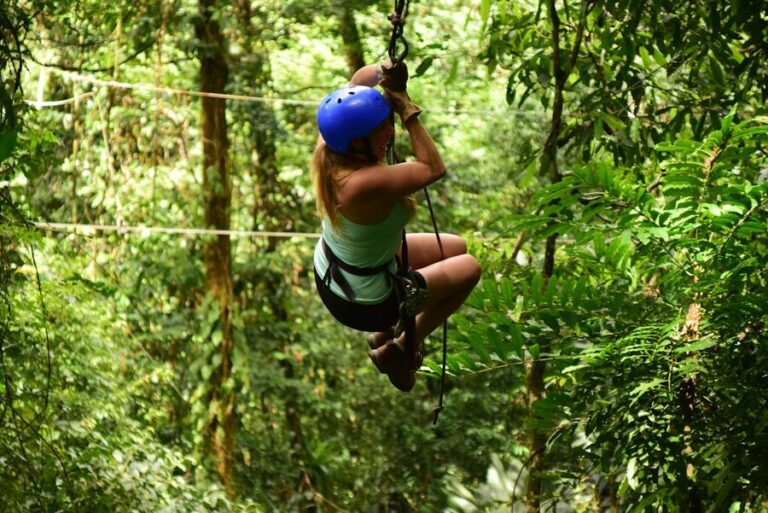 Woman ziplining through lush tropical forest canopy adventure