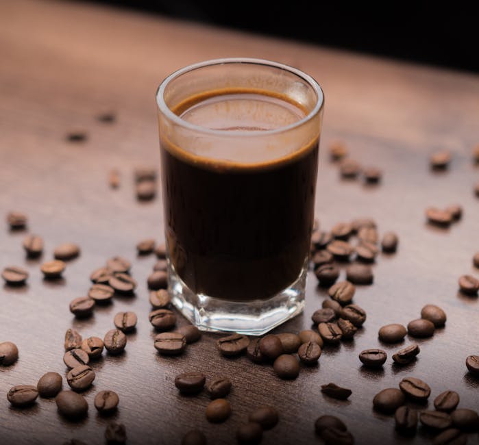 Rich espresso shot in a glass with scattered coffee beans