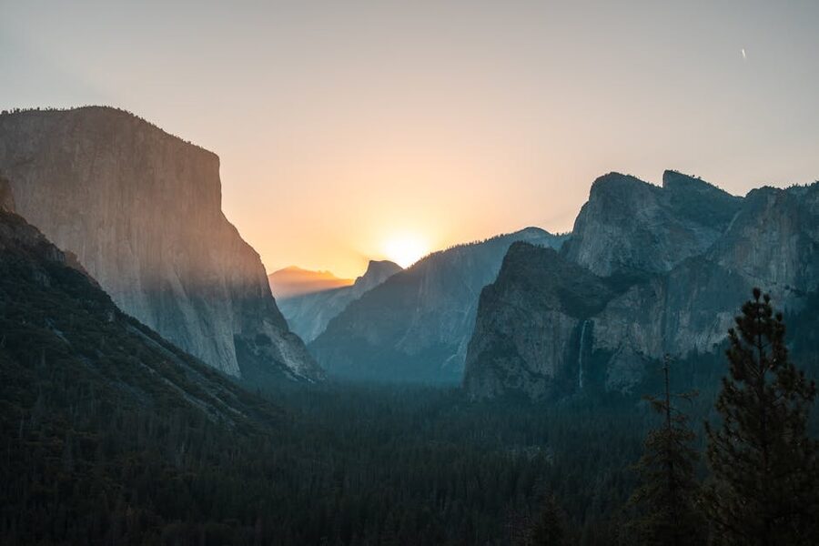 Sunrise light breaking over misty Yosemite Valley cliffs