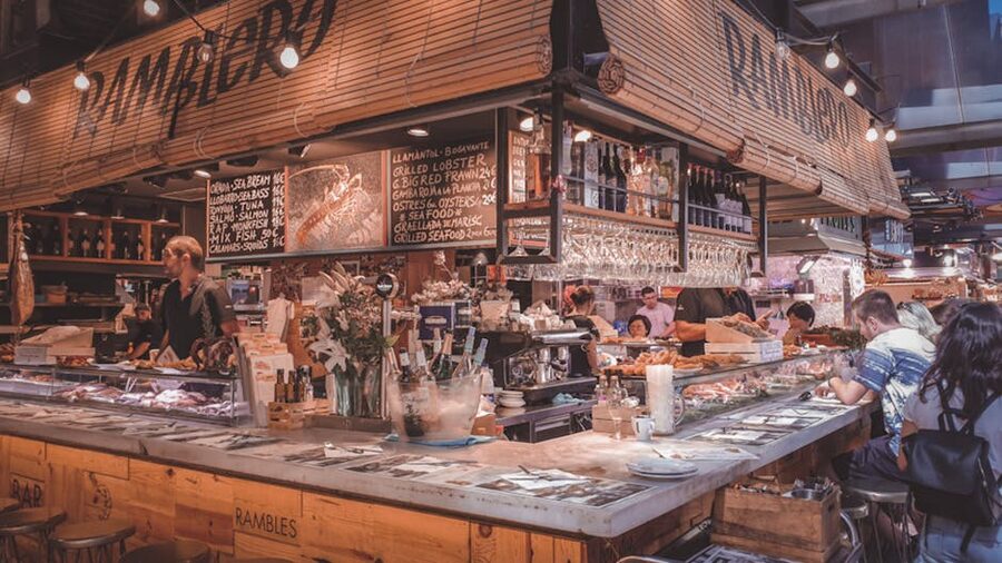 Lively counter food stall with bar stools at La Boqueria Barcelona