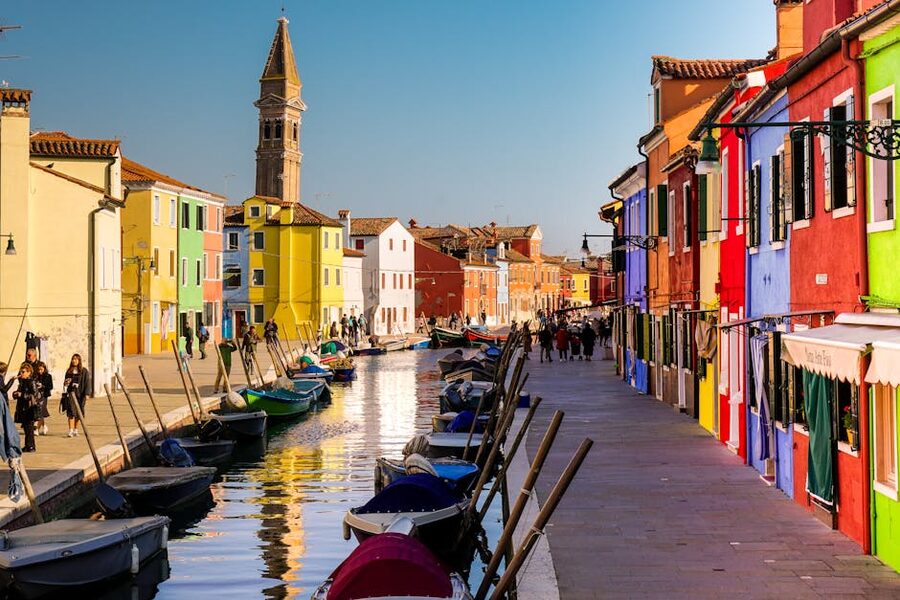 Boats moored along Burano canal with colourful house facades, Venice