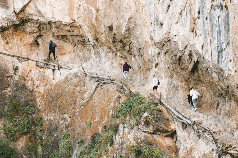 Hikers navigating a narrow rocky section of the Caminito del Rey