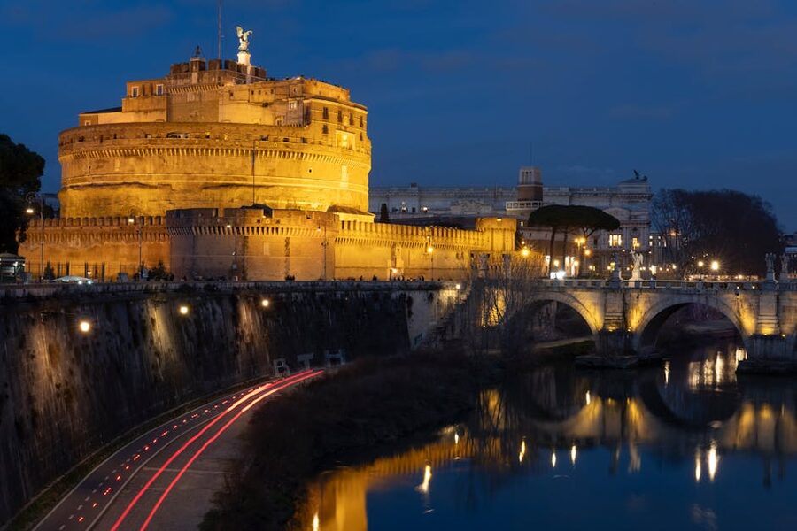 Castel Sant'Angelo illuminated at night with Ponte Sant'Angelo lights reflecting on the Tiber