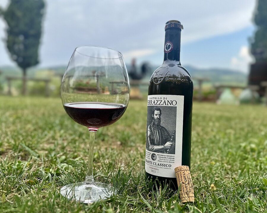 Glass and bottle of Chianti Classico Annata wine with vineyard background