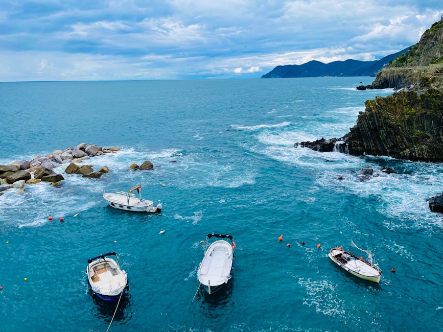 Boats anchored along rocky Ligurian coastline