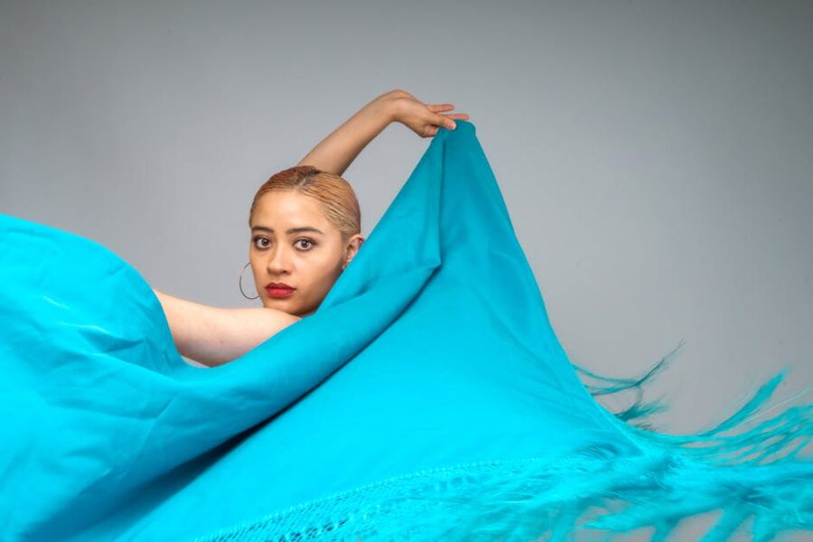 Flamenco dancer with flowing blue fabric in mid-performance