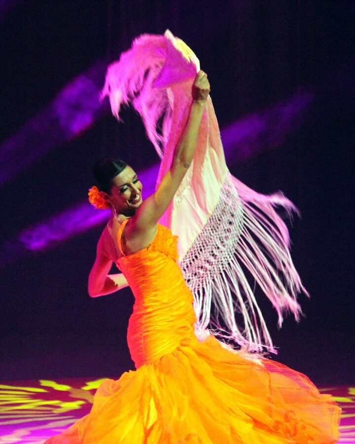 Flamenco dancer mid-performance on a Madrid tablao stage with theatrical lighting