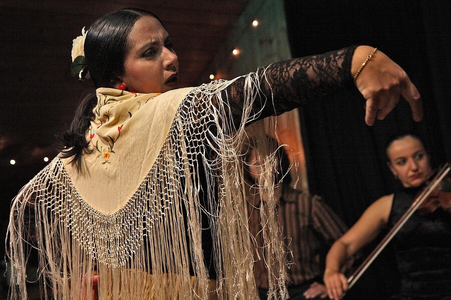 Flamenco dancer in traditional Spanish dress holding pose mid-show