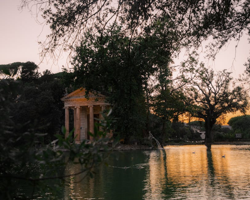 The Temple of Aesculapius reflected in a pond in Villa Borghese park at sunset