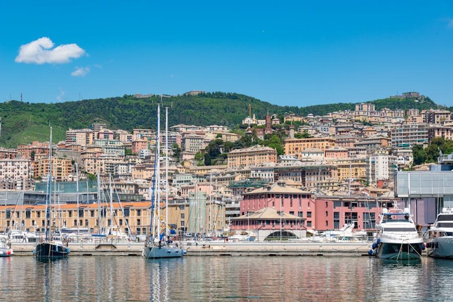 Genoa marina with sailboats and a hillside townscape rising behind
