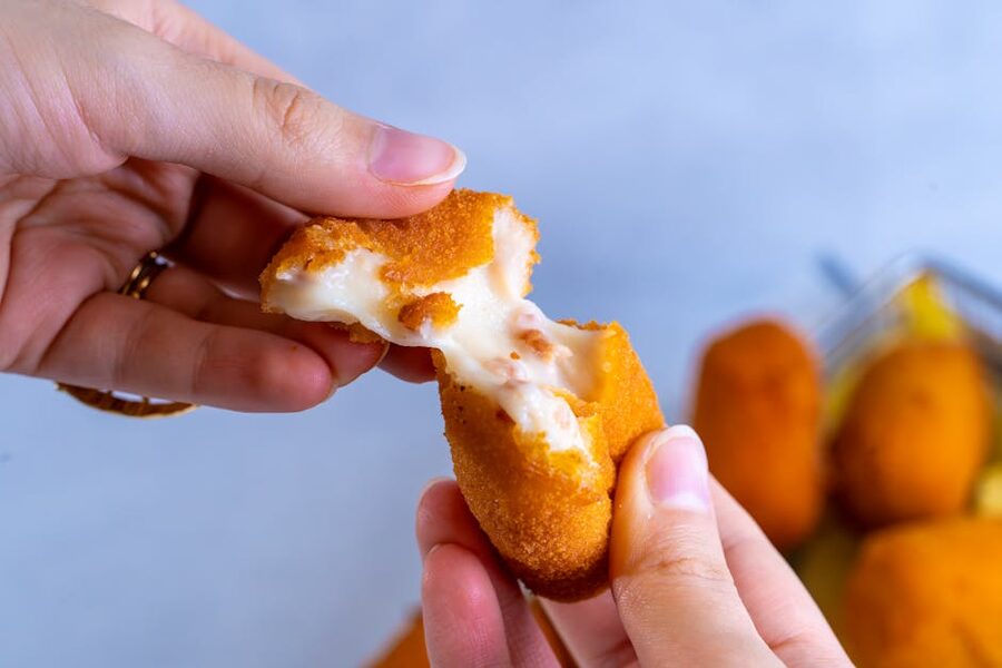 Croquette being broken open with melted cheese inside