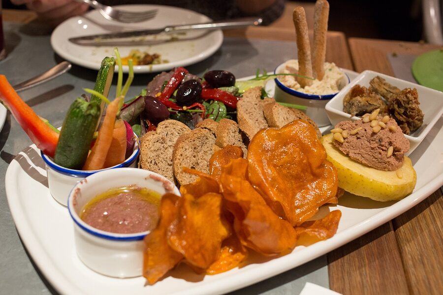 Vegetarian tapas spread on a board with bread and dips