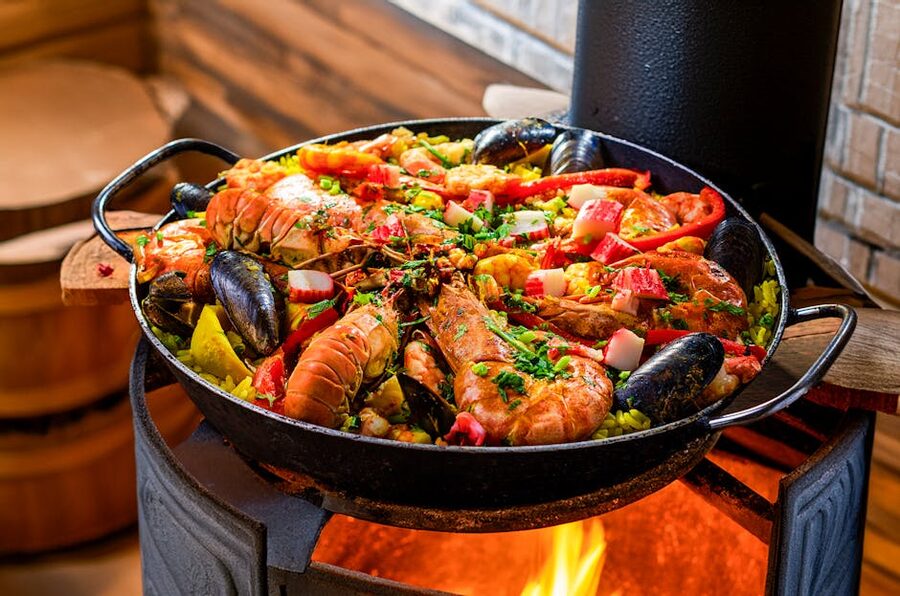 Paella cooking over an open flame in a wide pan