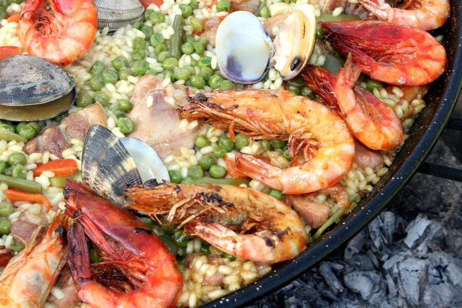 Paella with clams and shrimp cooking over fire