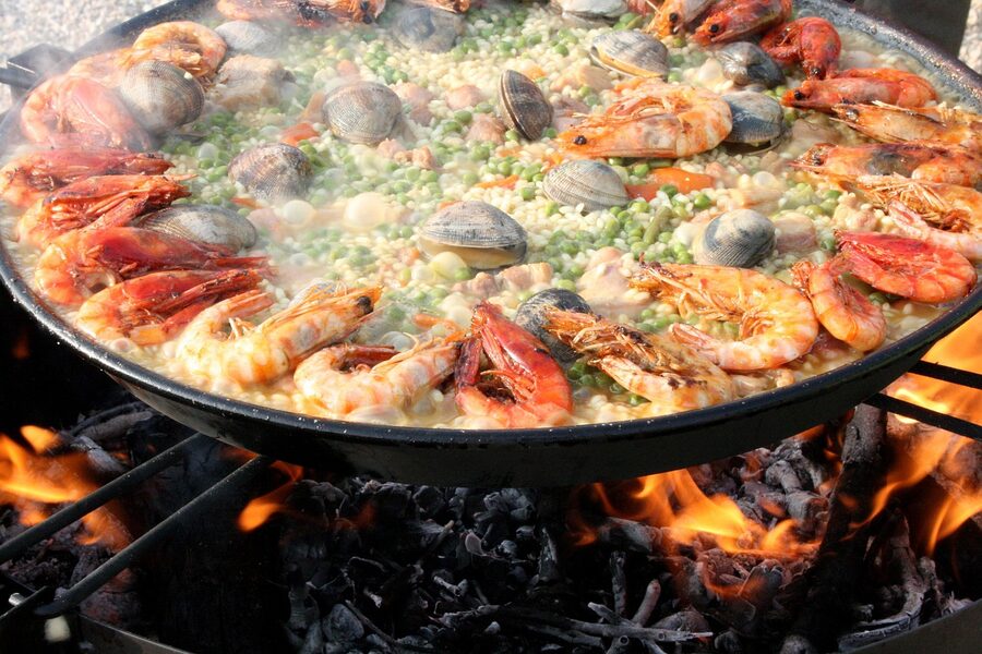 Mixed Valencian paella cooking over a wood fire