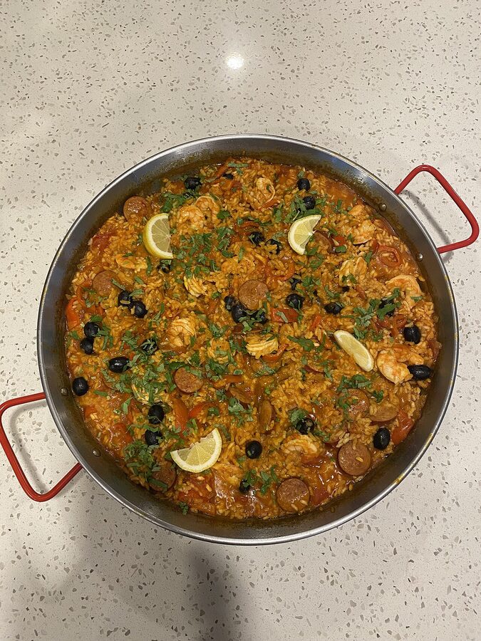 Traditional Valencian paella in a wide pan with chicken, rabbit, beans and saffron rice