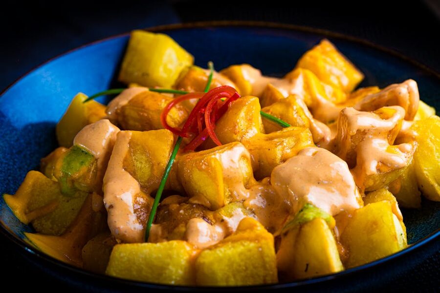 Patatas bravas with spicy aioli in a blue bowl Madrid