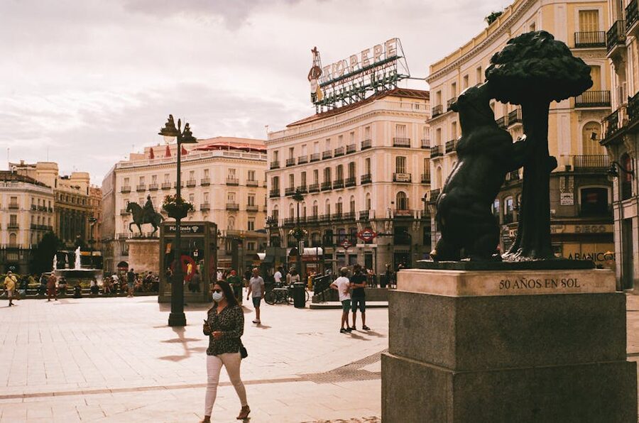 Bear and Strawberry Tree statue at Puerta del Sol Madrid with people walking past