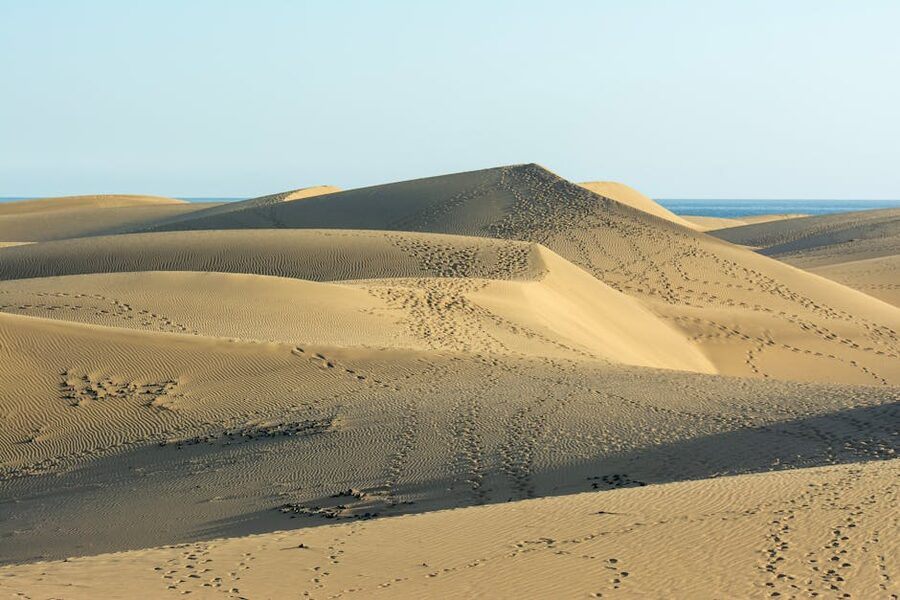 Maspalomas dunes with deep footprints in pale sand under summer sun