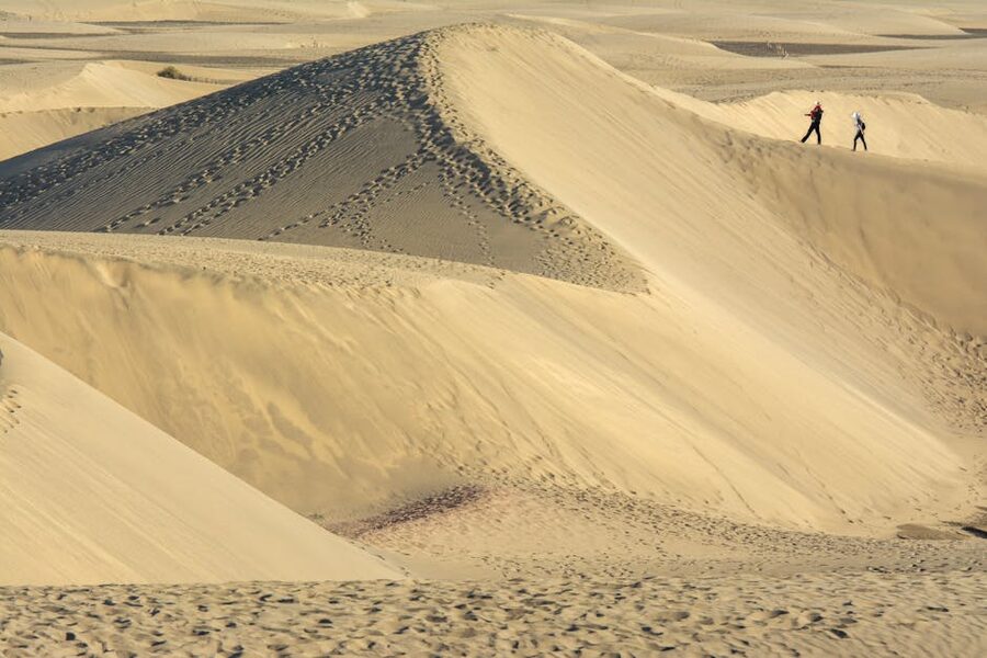 Two people walking across the Maspalomas sand dunes Gran Canaria