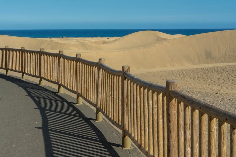 Wooden boardwalk leading through Maspalomas dunes towards the beach